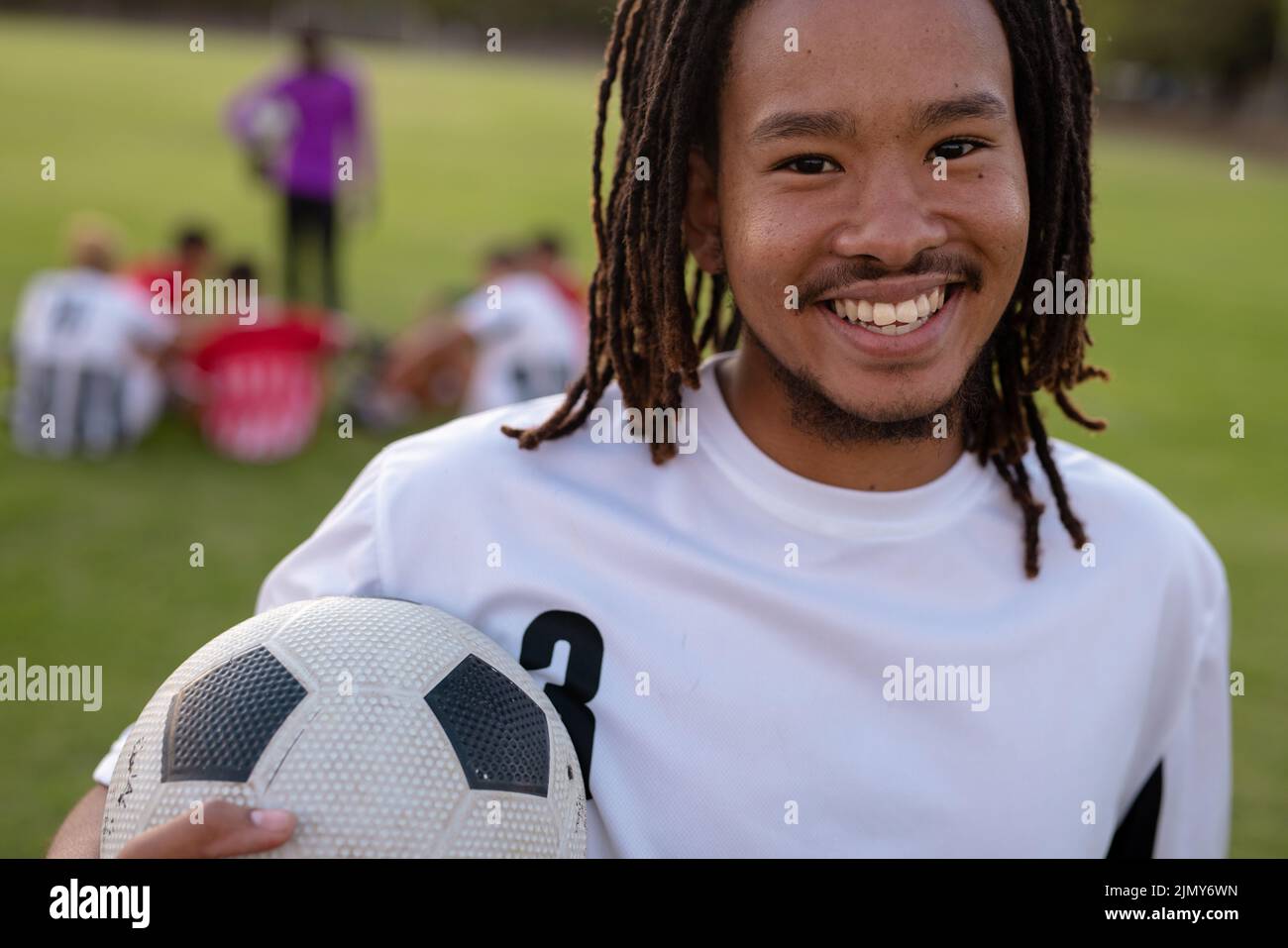 Close-up portrait of biracial male player with dreadlocks holding ...