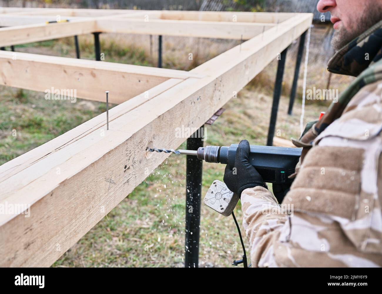 Man building wooden house on pile foundation. Close up of male worker ...