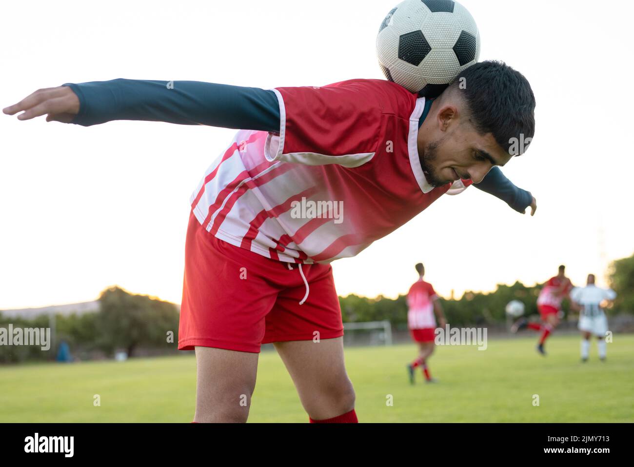 Caucasian young male player with soccer ball on back bending and ...