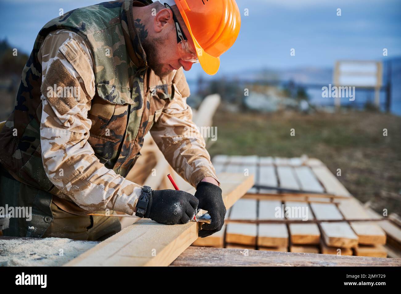 Man worker building wooden frame house. Carpenter measuring wooden ...