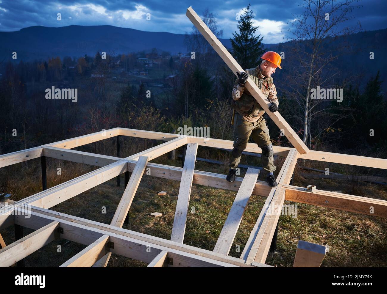 Man worker building wooden frame house on pile foundation. Carpenter ...