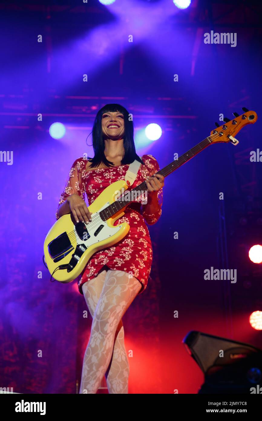 Bassist Laura Lee of Khruangbin on stage wearing a red floral mini dress with white stockings ...