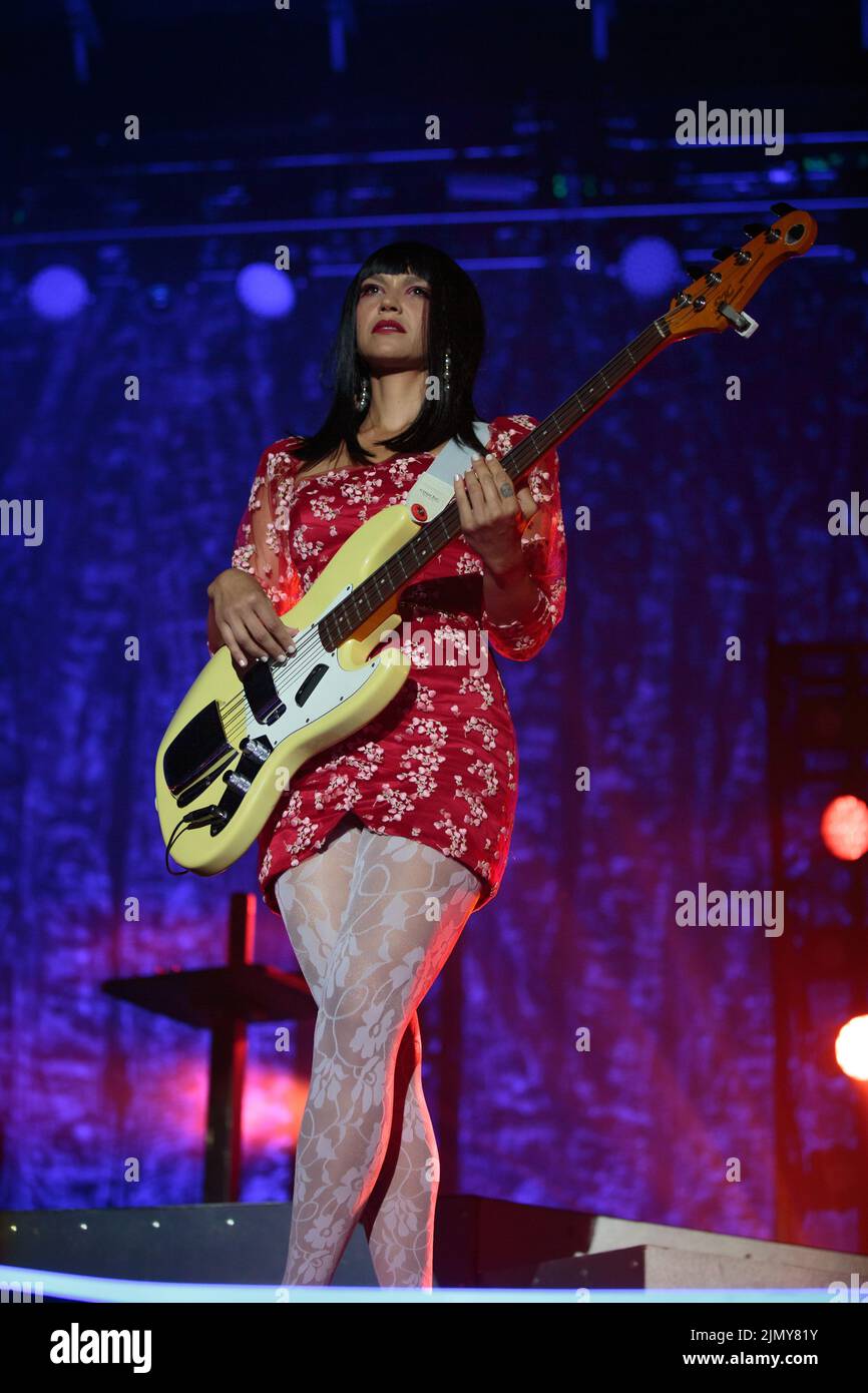 Bassist Laura Lee of Khruangbin on stage wearing a red floral mini dress with white stockings ...