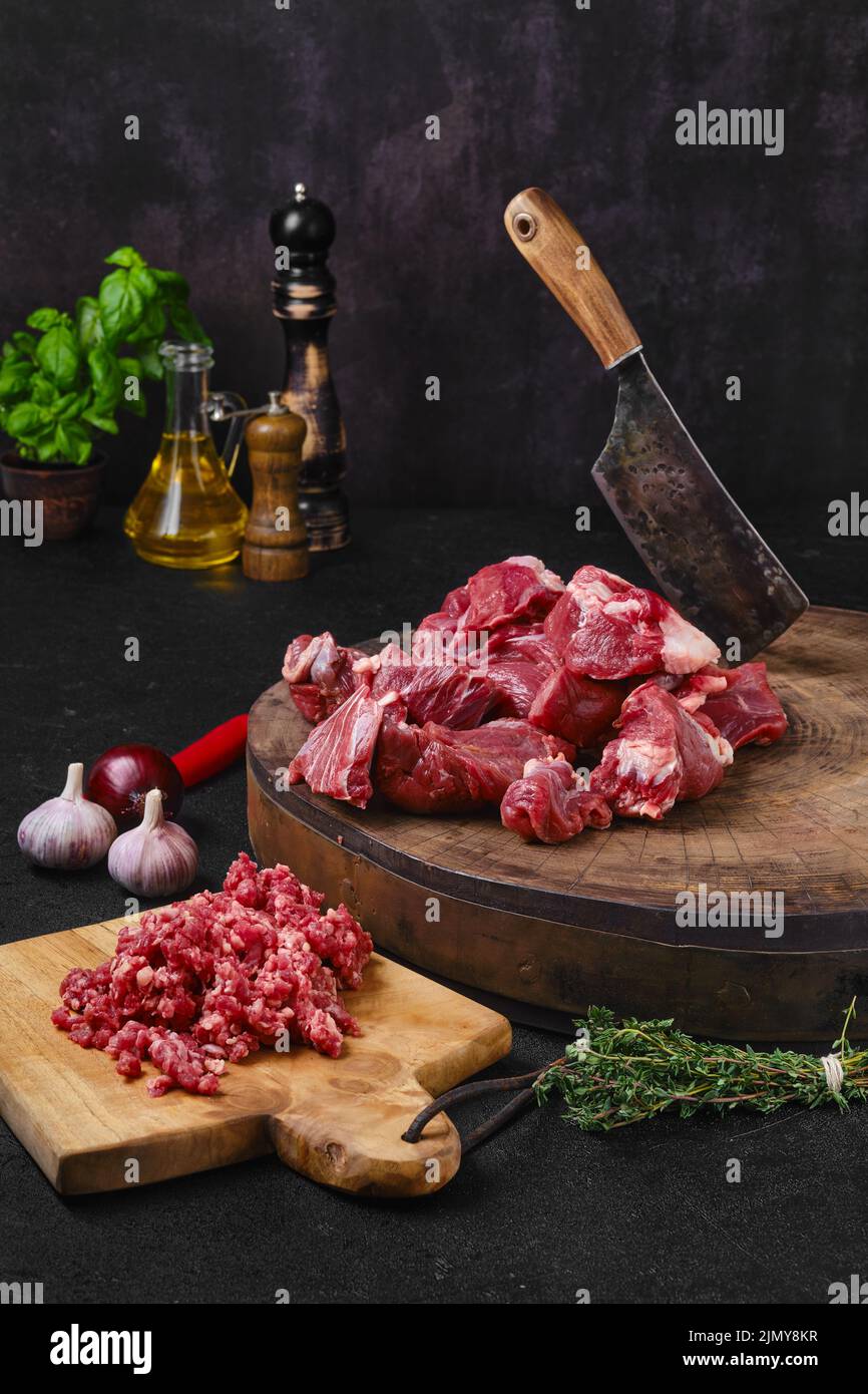 Chopping fresh beef meat for goulash or stew on wooden chopping stump ...