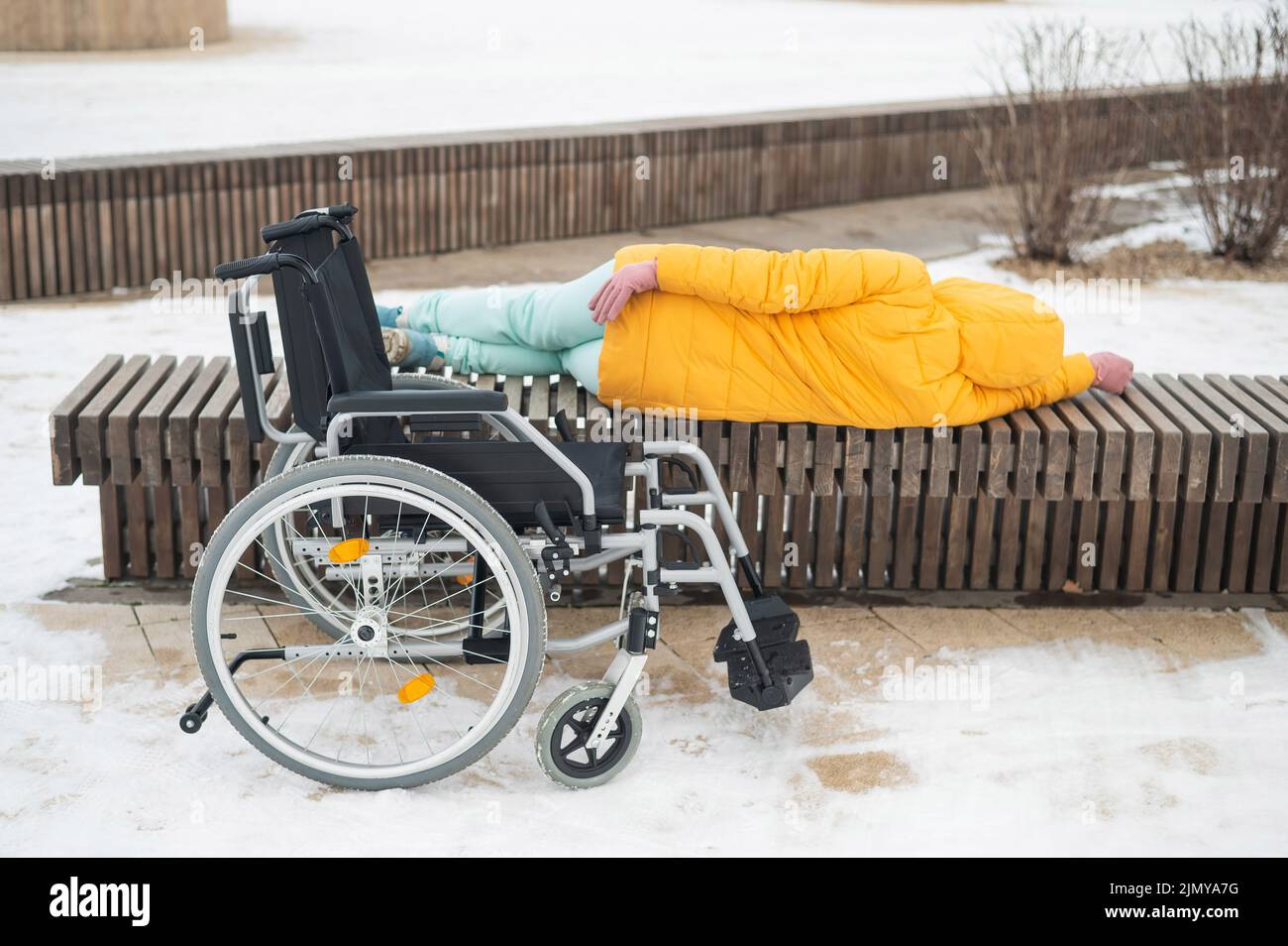 Homeless woman sleeping on a park bench next to a wheelchair Stock ...