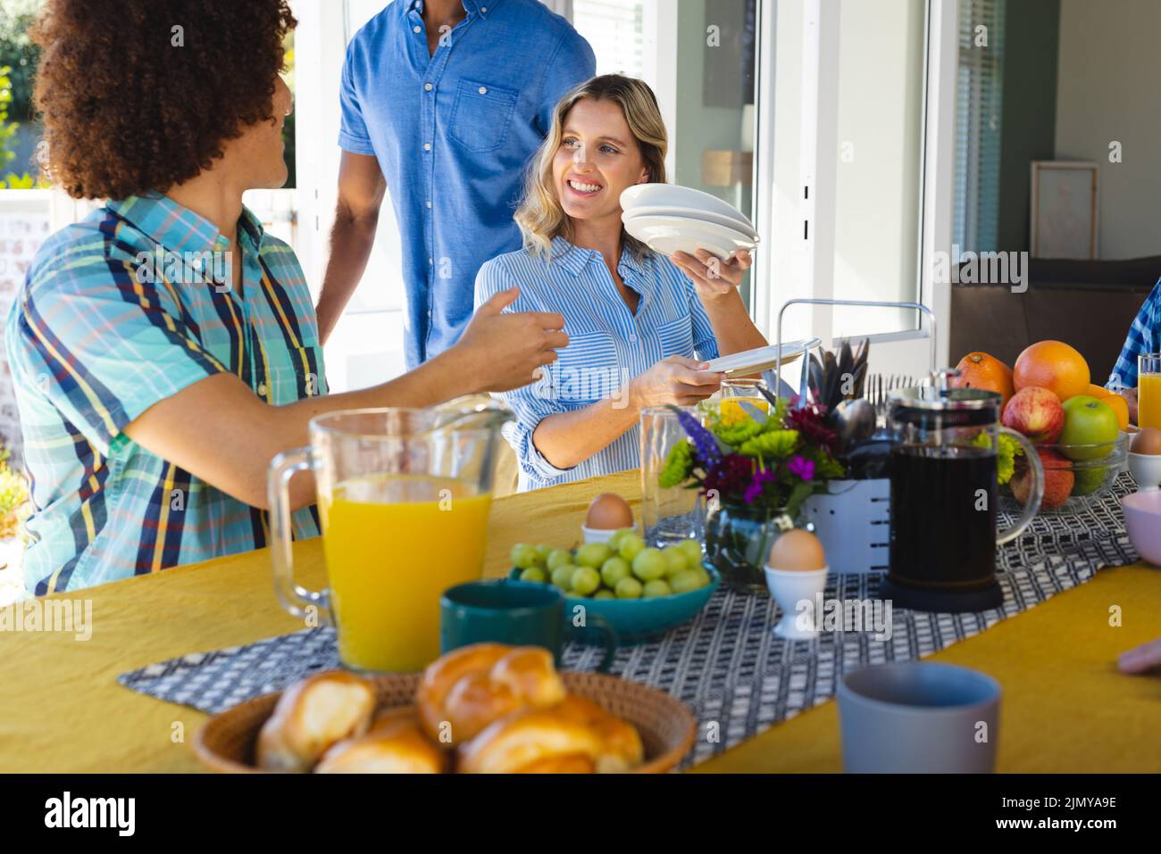 Caucasian young woman passing plates to biracial young man while having ...