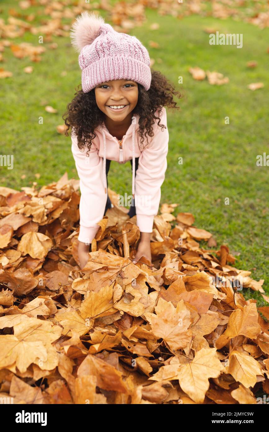 Vertical image of happy african american girl having fun with leaves in garden Stock Photo - Alamy