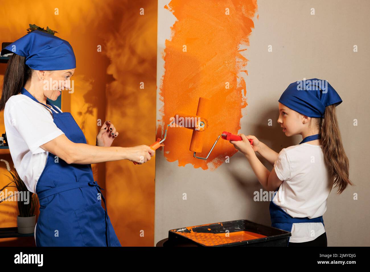 Young people having fun with orange paint, painting apartment walls ...