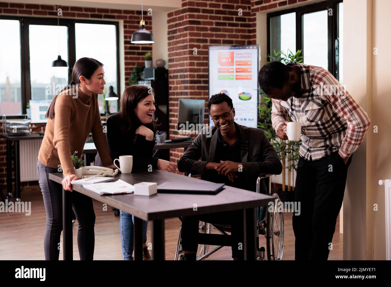 Entrepreneur sitting in wheelchair and talking to business partners on ...