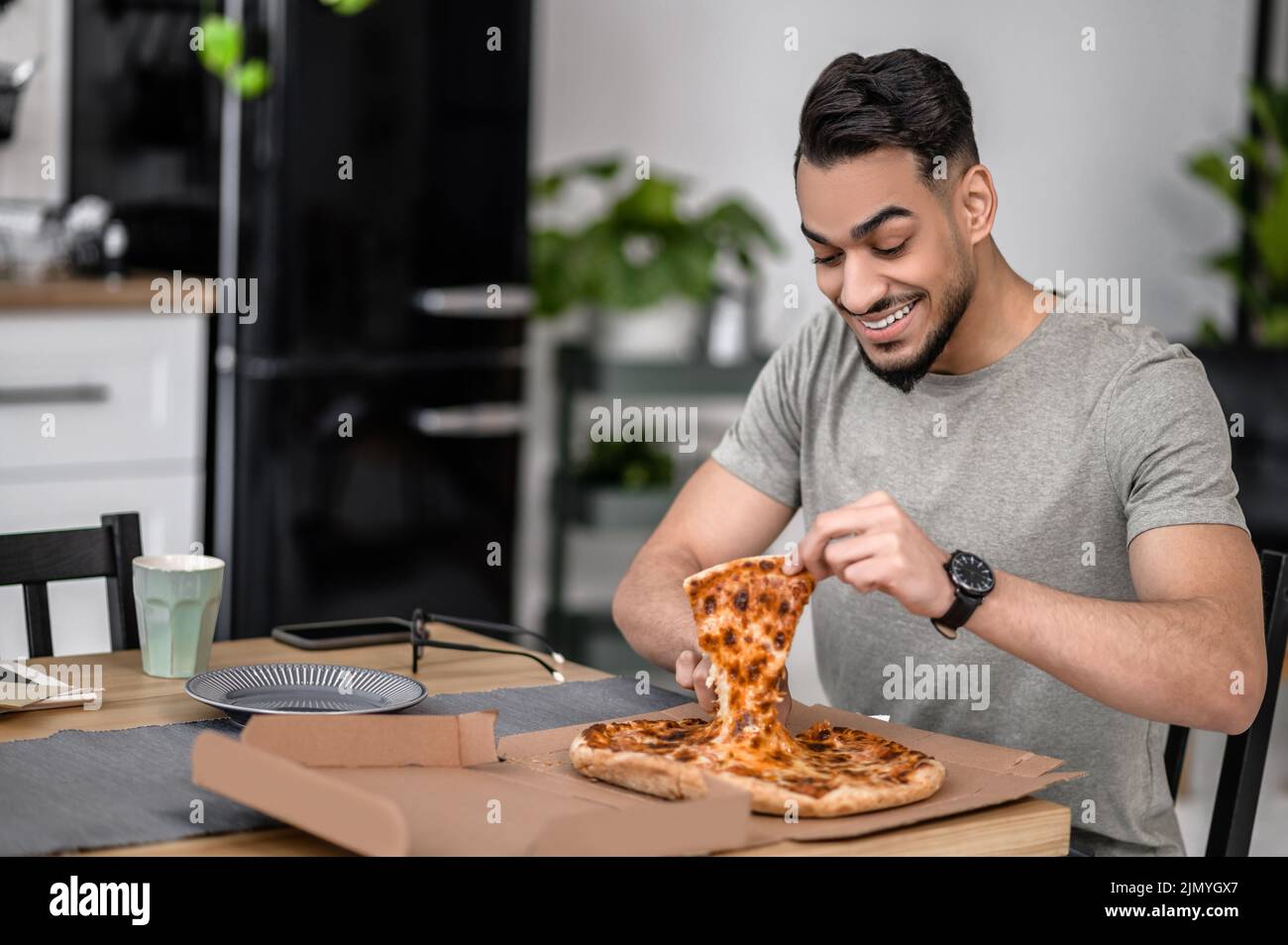 Man looking with delight at pizza taking slice Stock Photo - Alamy
