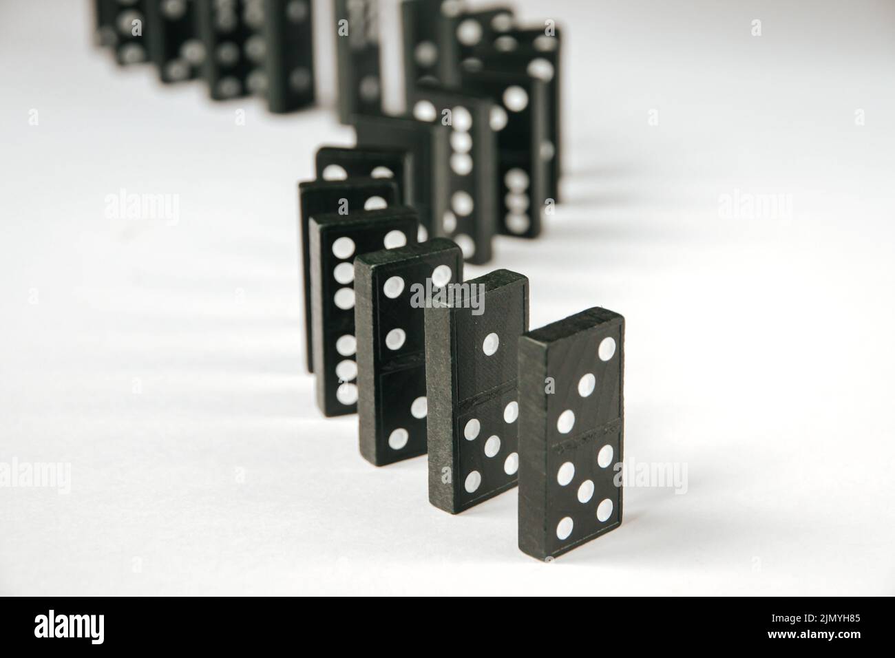 Black dominoes chain on a white table background. Domino effect concept ...