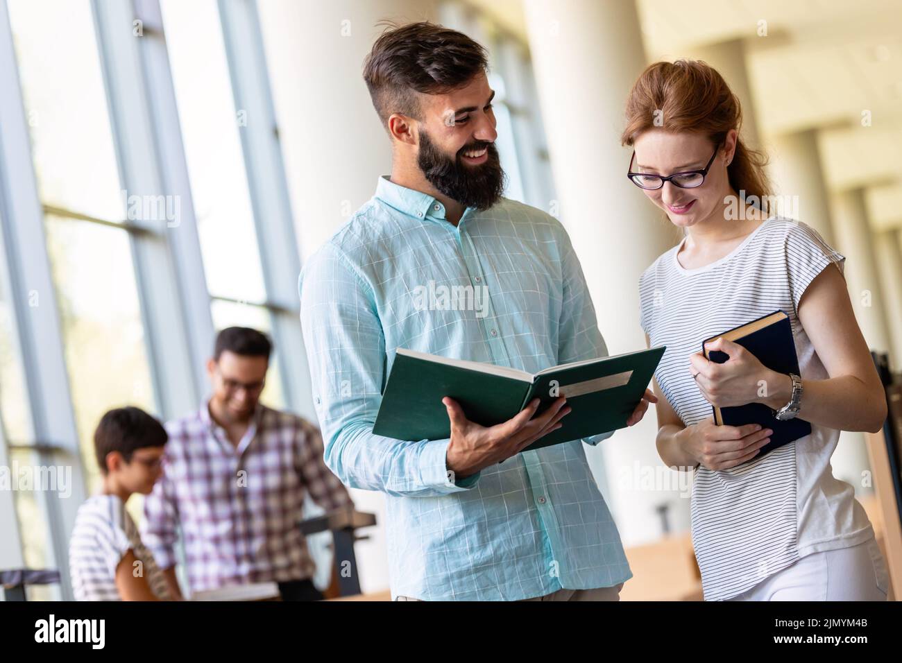 Happy university students studying with books in library. Group of ...