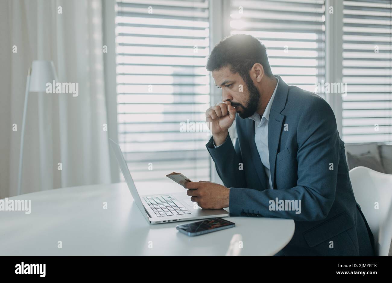 Depressed businessman man counting euro money working on computer at ...
