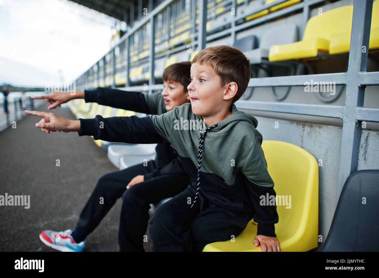 Two brothers support their favorite team, sitting on the sports podium ...