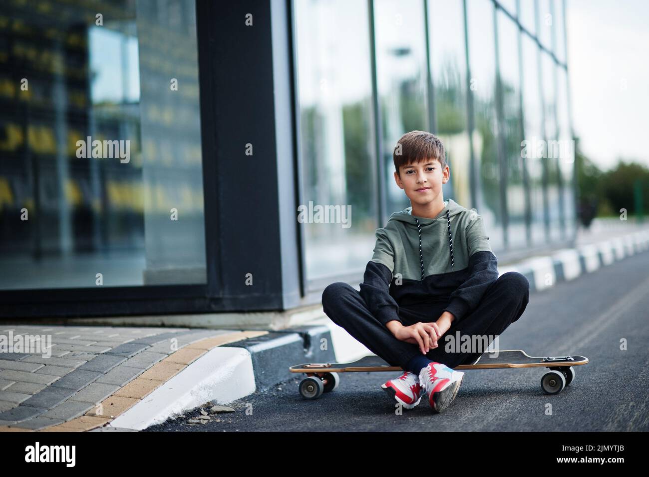 Teenager boy in a sports suit with longboard Stock Photo - Alamy