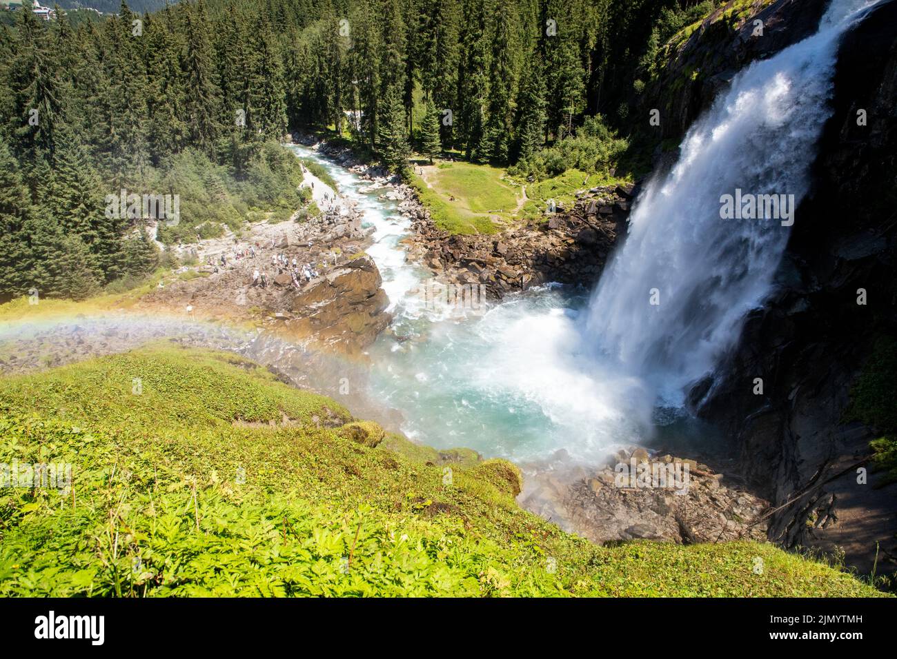 A rainbow over Krimmel waterfall flowing down the rocks covered with ...