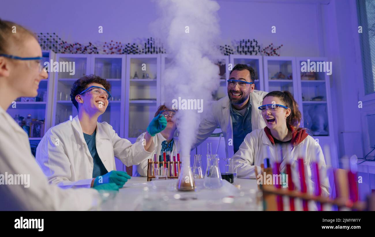 Excited science students with teacher doing chemical experiment in the ...
