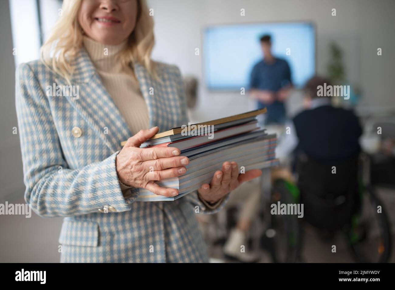 Happy senior woman student posing with books in classroom Stock Photo ...