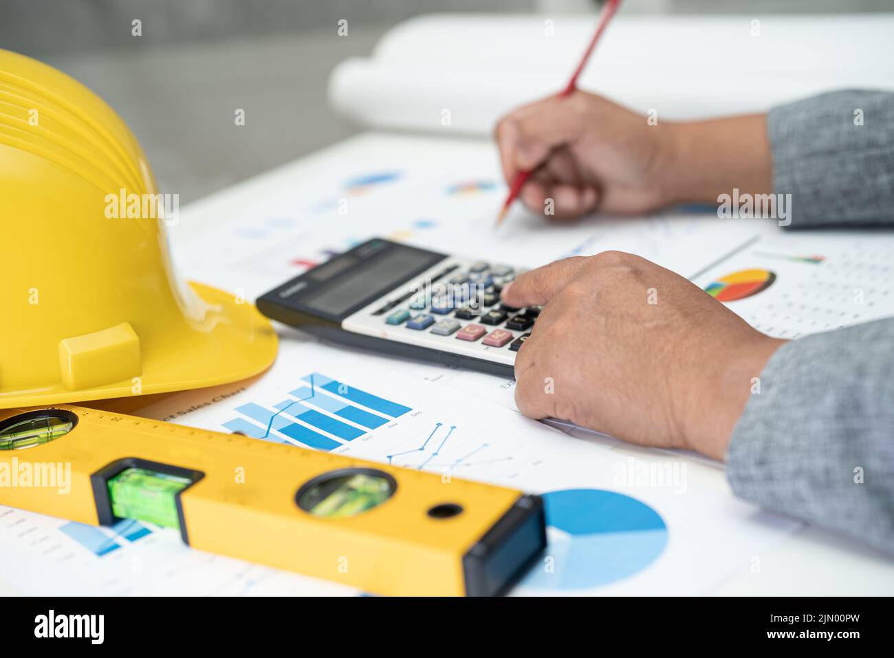 Asian engineer with plan project blueprint, graph and yellow helmet and ...