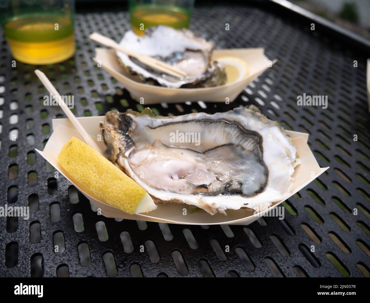 Raw oyster in the pearly shell with lemon on the paper plate Stock ...