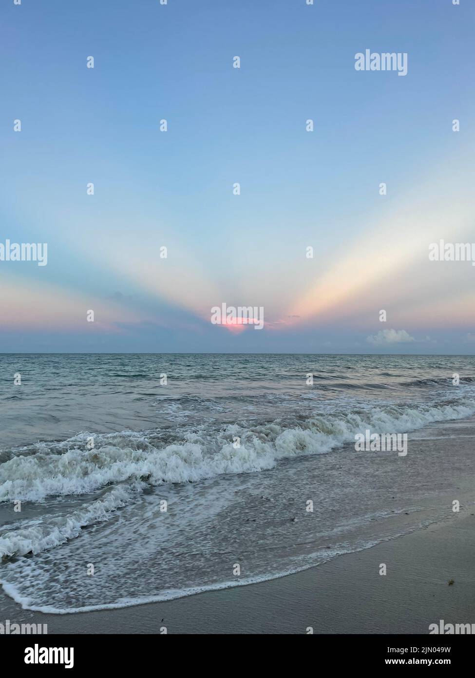 The beautiful sunset in the wavy beach Stock Photo - Alamy