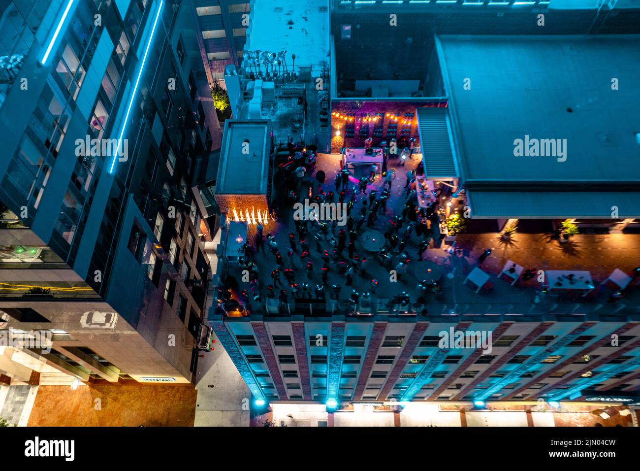 A high angle shot of a party on a rooftop of a skyscraper illuminated ...