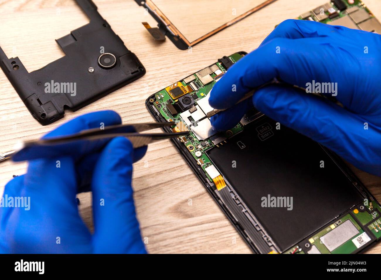 The technician repairing the smartphone's motherboard in the workshop ...
