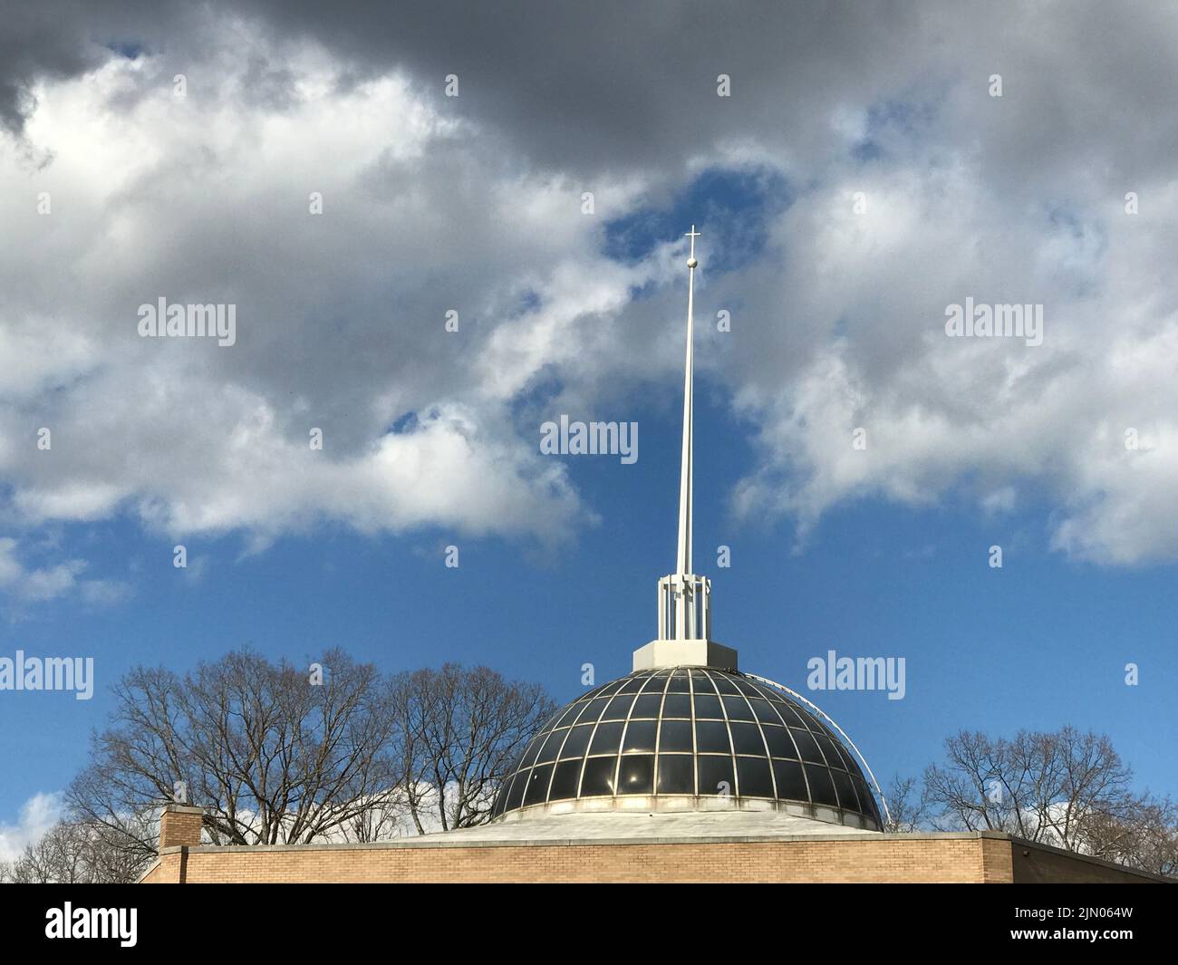 The low-angle view of a round spire with a cross on top under the blue ...