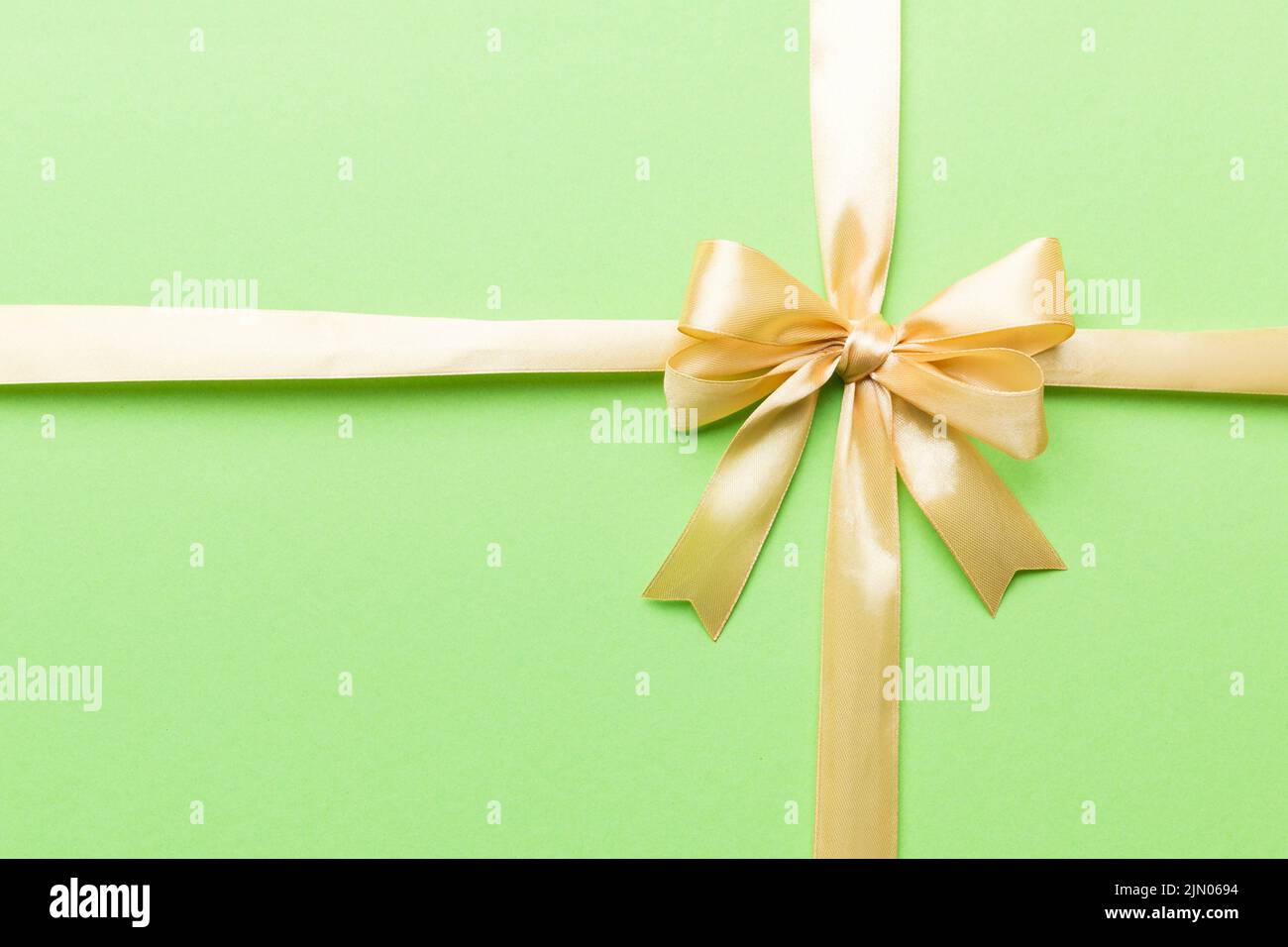 Top view of gold ribbon rolled and yellowbow isolated on colored ...