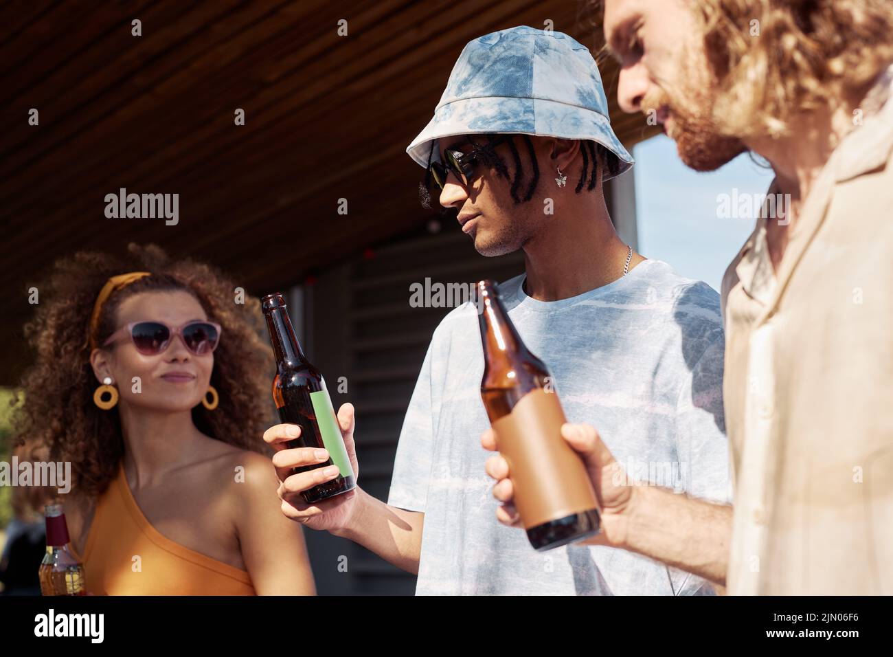 Diverse group of three young people enjoying refreshing drinks outdoors ...