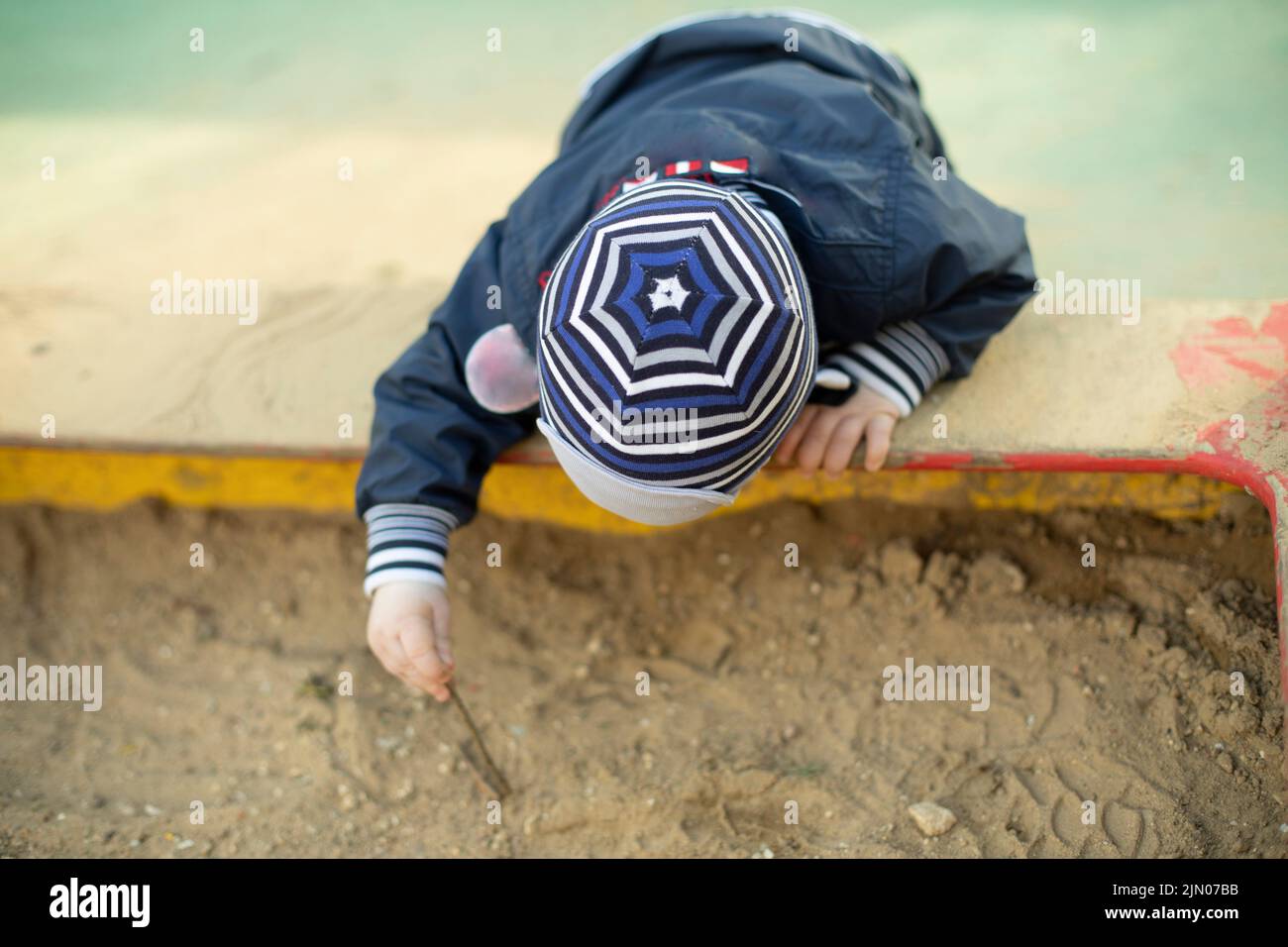Child in sandbox. Preschooler on playground. Little boy digs ground ...