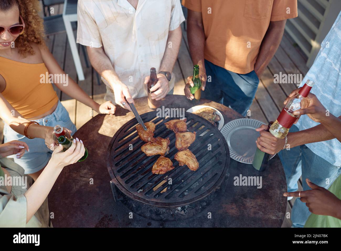 High angle at group of young people grilling chicken meat during ...