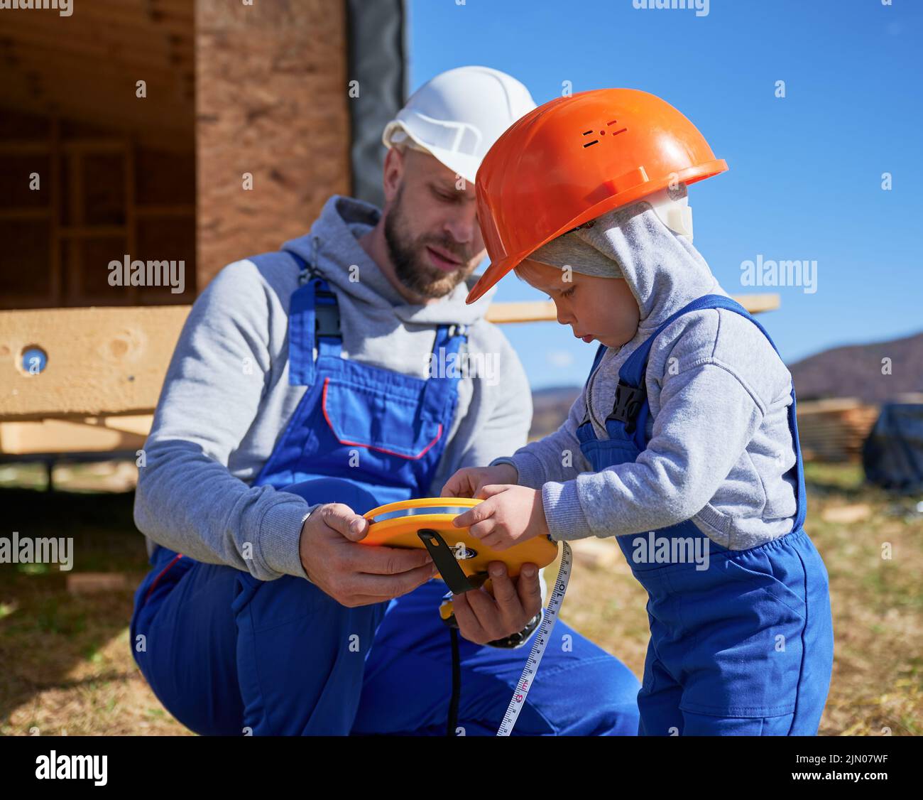 Father with toddler son building wooden frame house. Male builder and ...