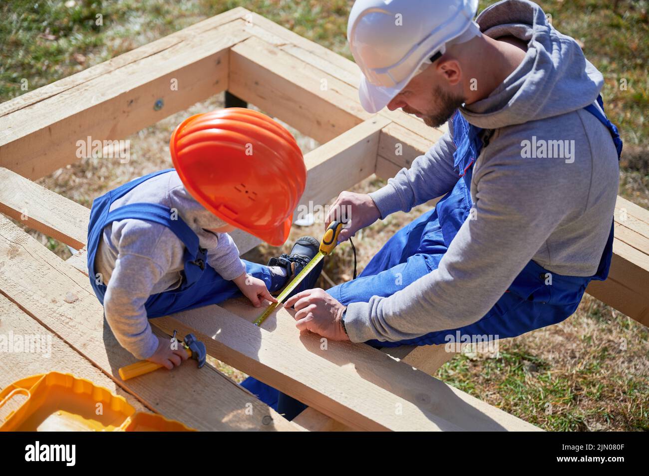 Father with toddler son building wooden frame house. Male builder and ...