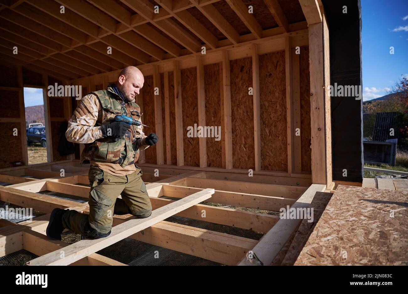 Male builder working with screwdriver inside of future cottage. Man ...