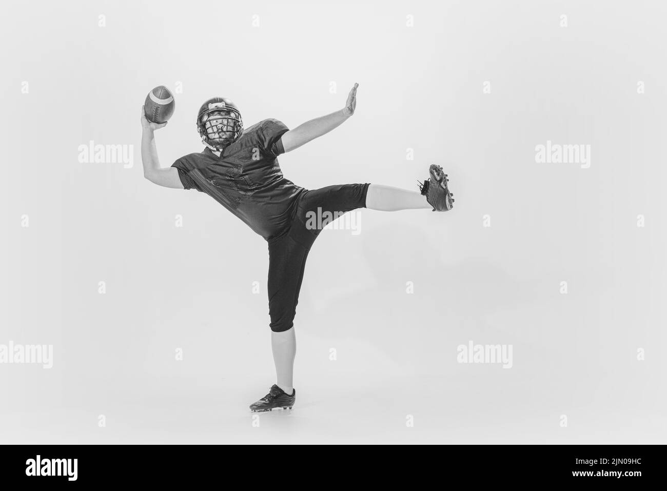 Studio shot of american football player training with ball isolated on ...