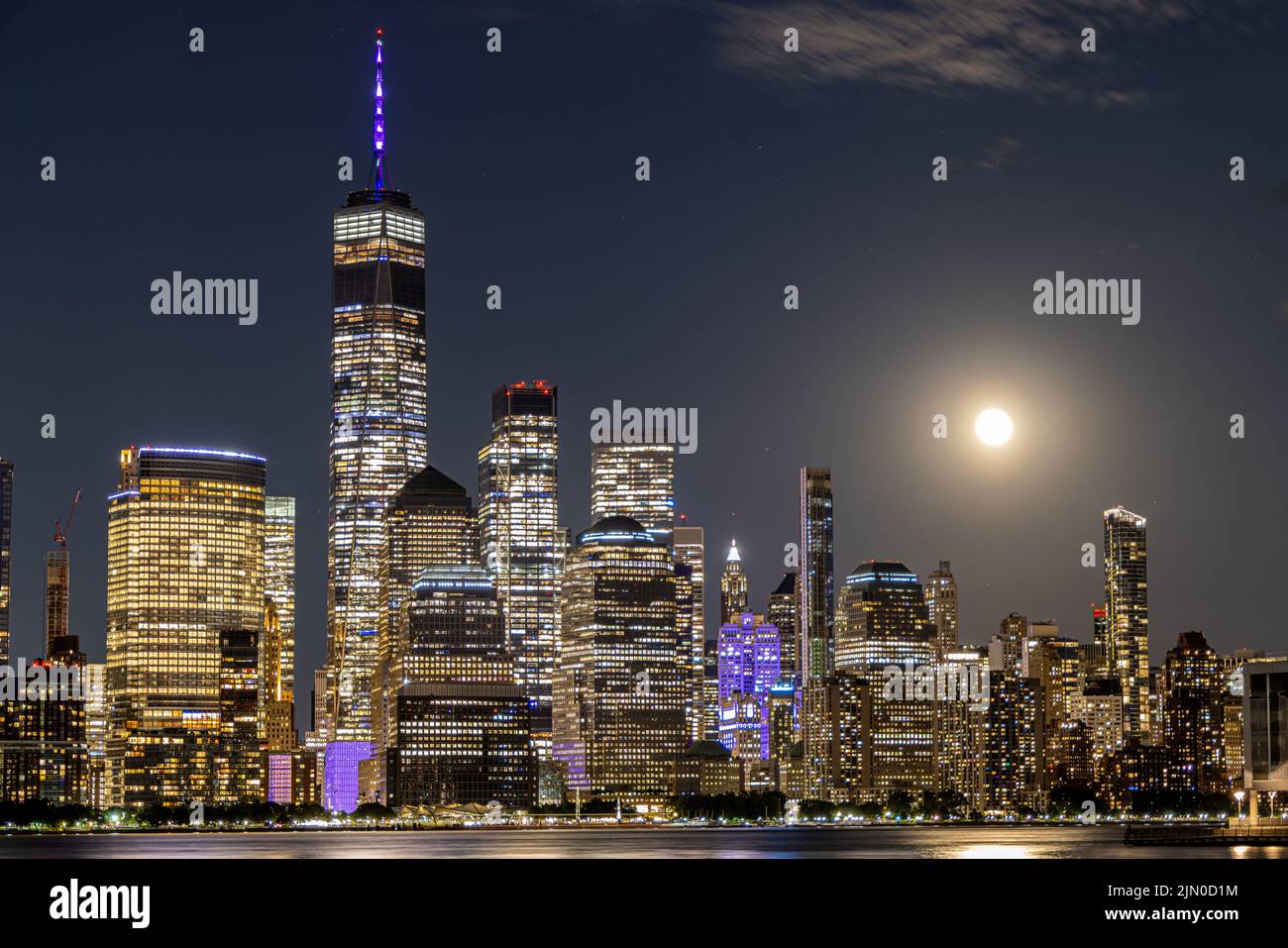 The cityscape of New York City buildings at night with the full moon in ...