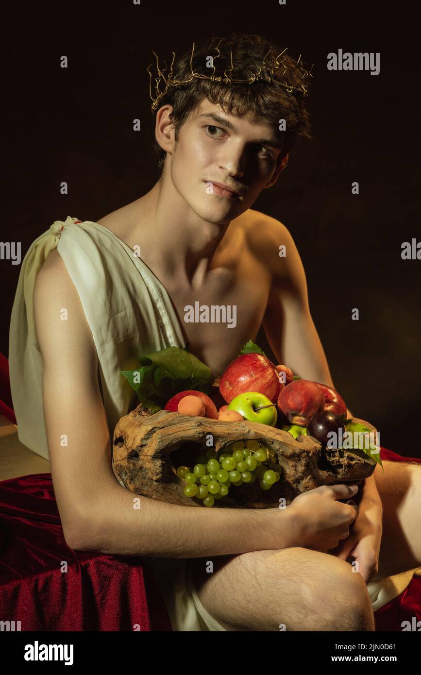 Creative remake of painting boy with a basket of fruit. Young handsome ...