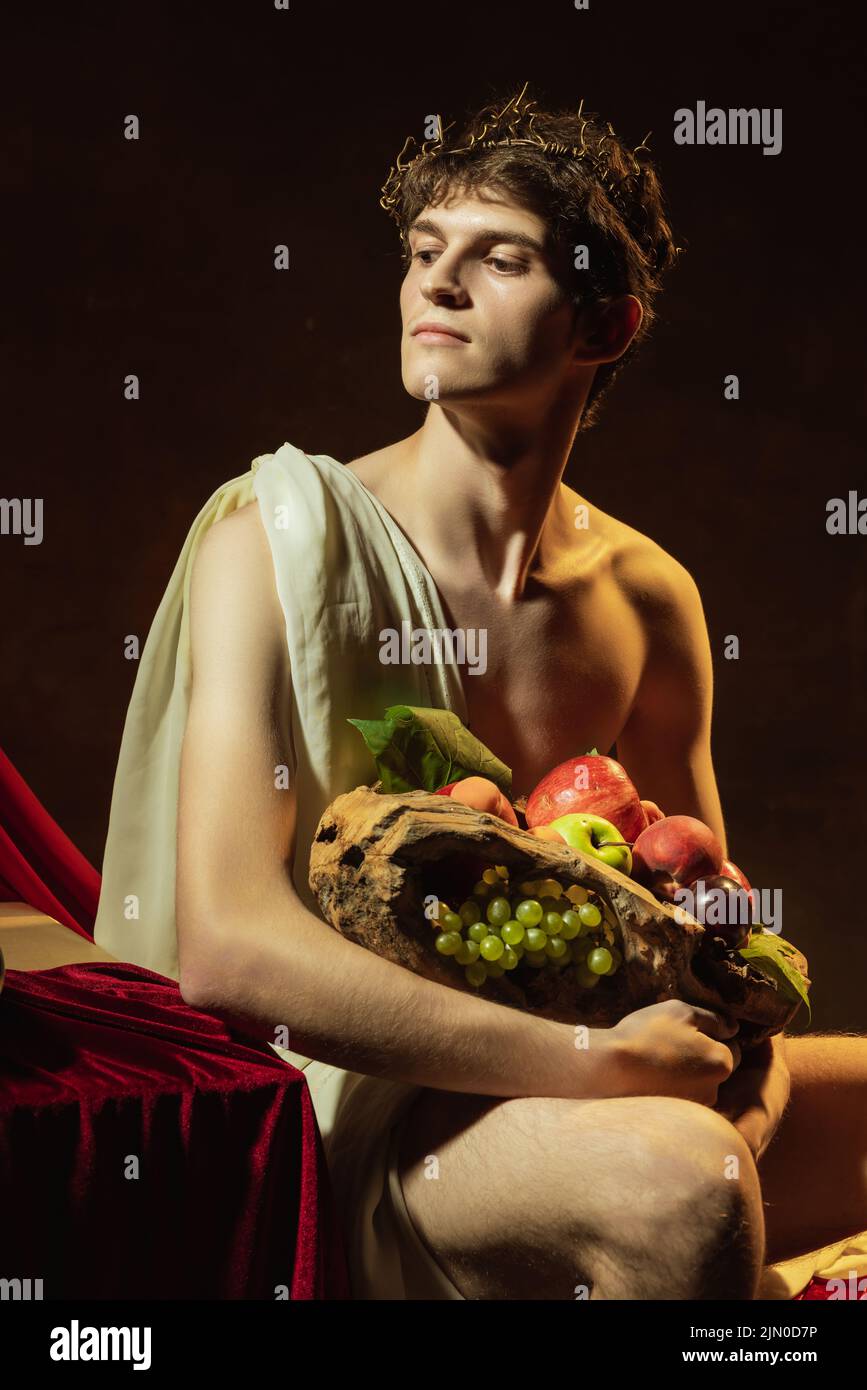 Creative remake of painting boy with a basket of fruit. Young handsome ...