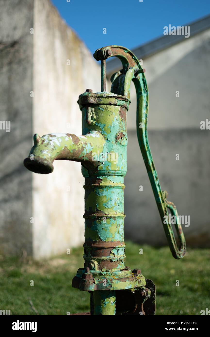 Old hand water pump on a well in the garden, watering and saving water ...