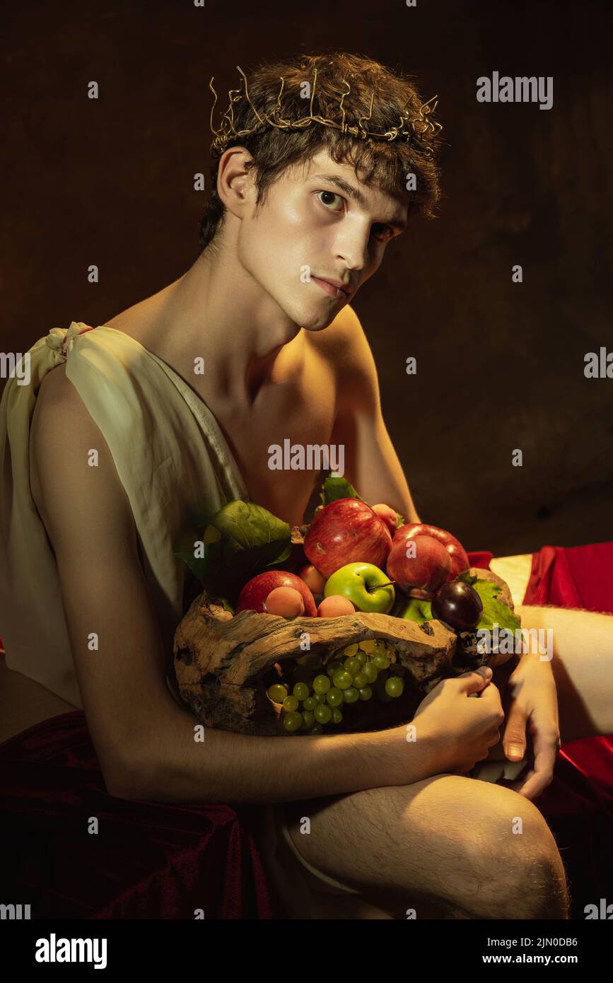 Creative remake of painting boy with a basket of fruit. Young handsome ...
