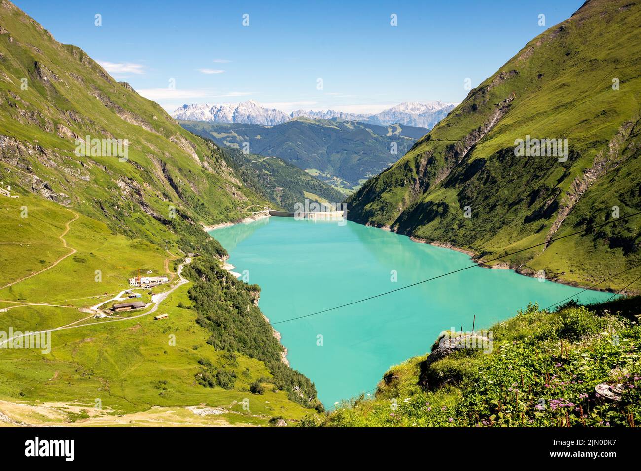 A high angle shot of a water dam in green mountains of the Alps ...
