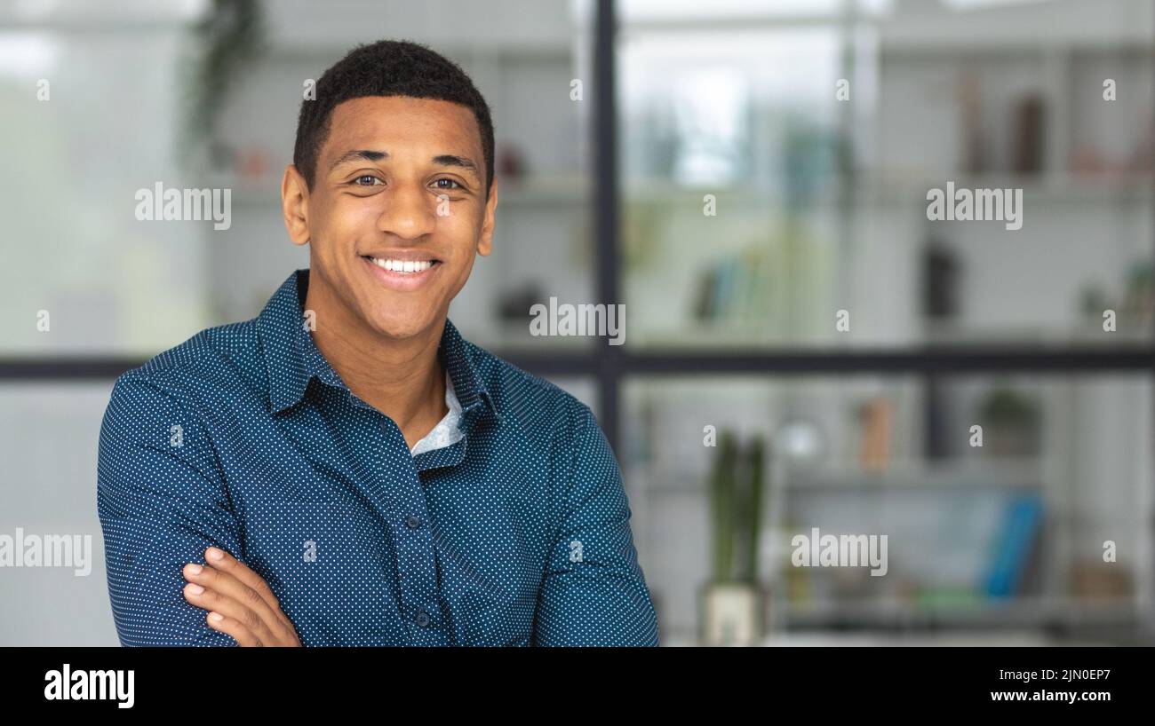 Successful young African American businessman with arms crossed standing in modern office Stock ...