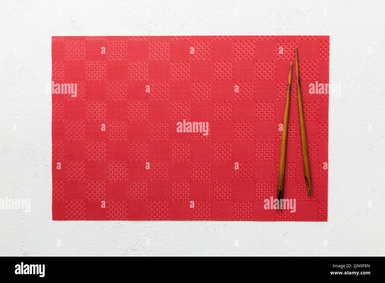 Two chopsticks and bamboo mat on cement background. Top view, copy ...