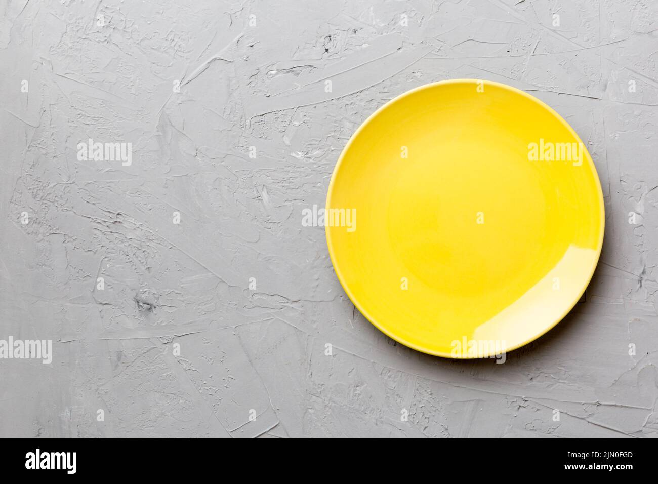 Top view of empty yellow plate on cement background. Empty space for ...