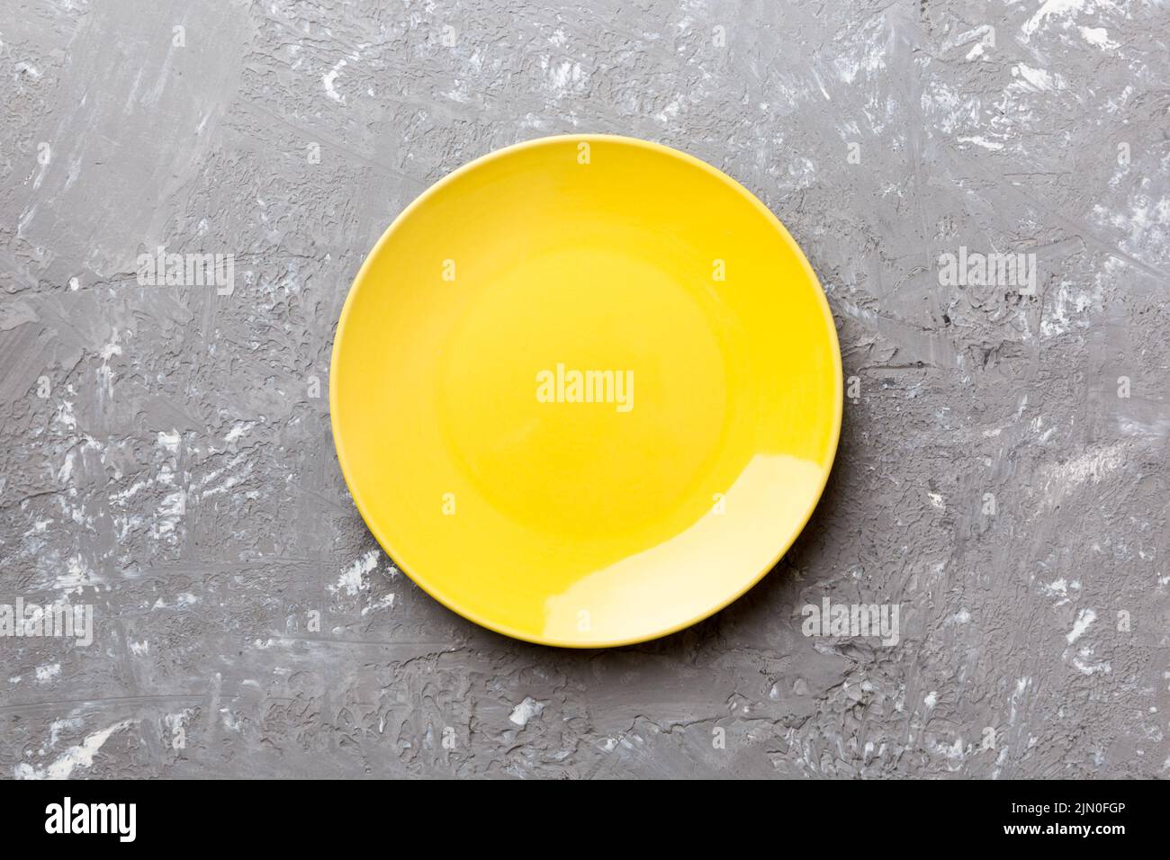 Top view of empty yellow plate on cement background. Empty space for ...