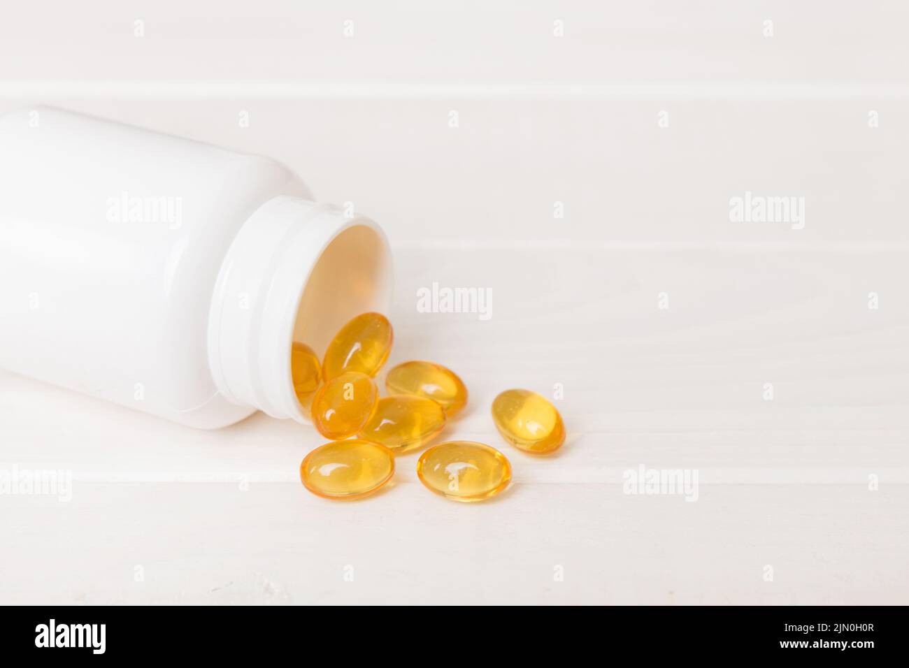 Omega-3 capsules lie in white bottle on a table background. Fish oil ...