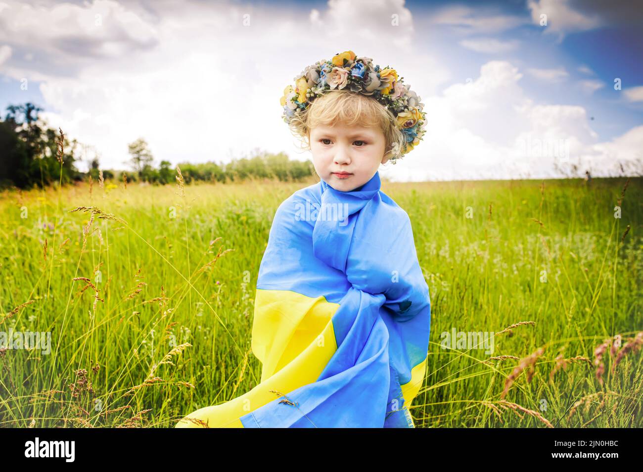 little sad Ukrainian girl wrapped in Ukrainian flag. child with a ...