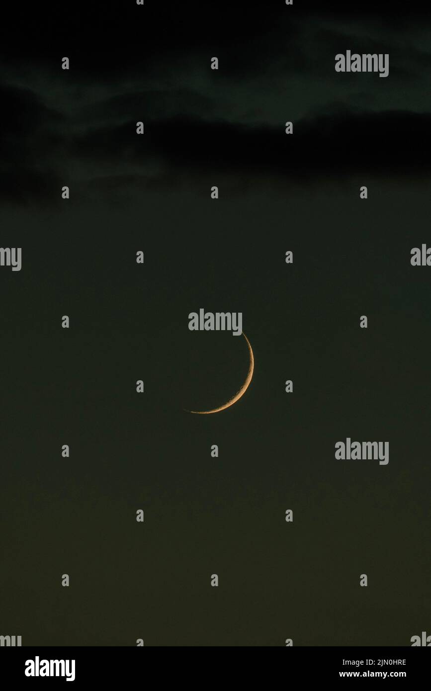 A vertical shot of the bright crescent Moon in the night sky background ...