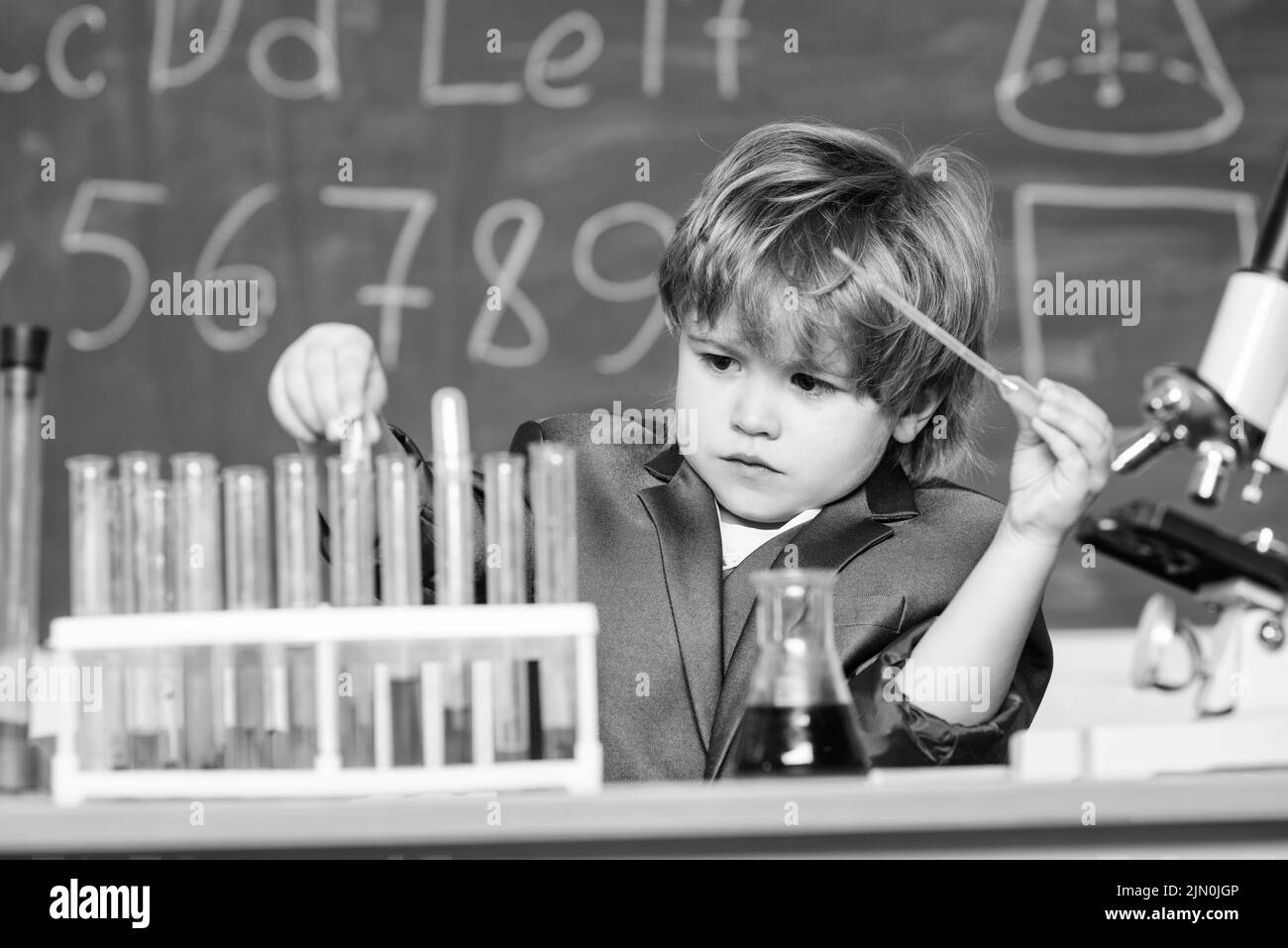 Wunderkind experimenting with chemistry. Boy test tubes liquids ...